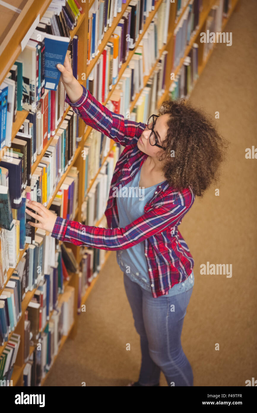 Pretty student in library taking book Stock Photo - Alamy
