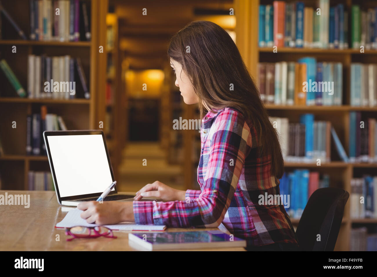 Female student using laptop while writing on book Stock Photo - Alamy