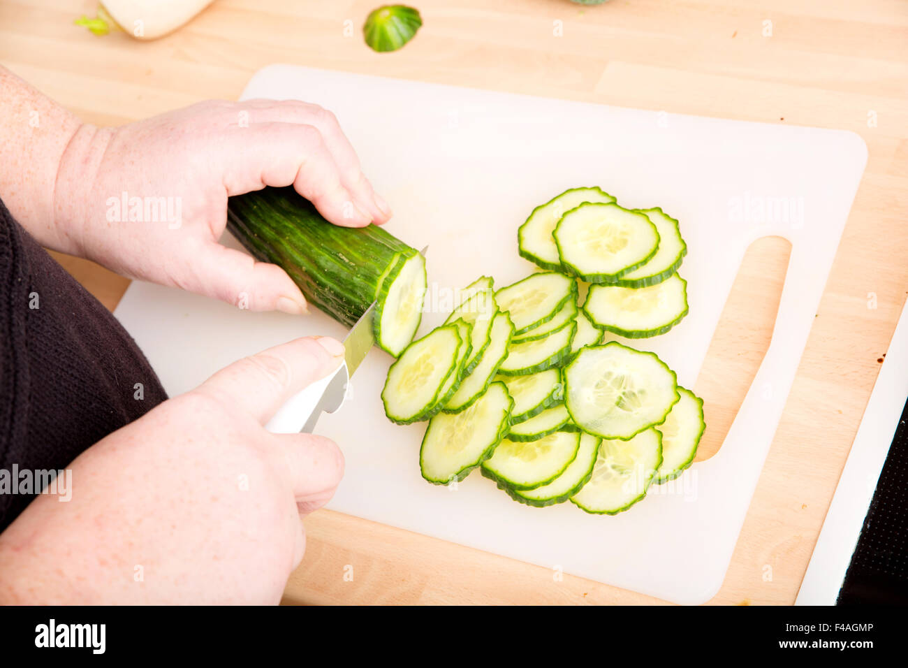 Woman cutting cucumber Stock Photo - Alamy