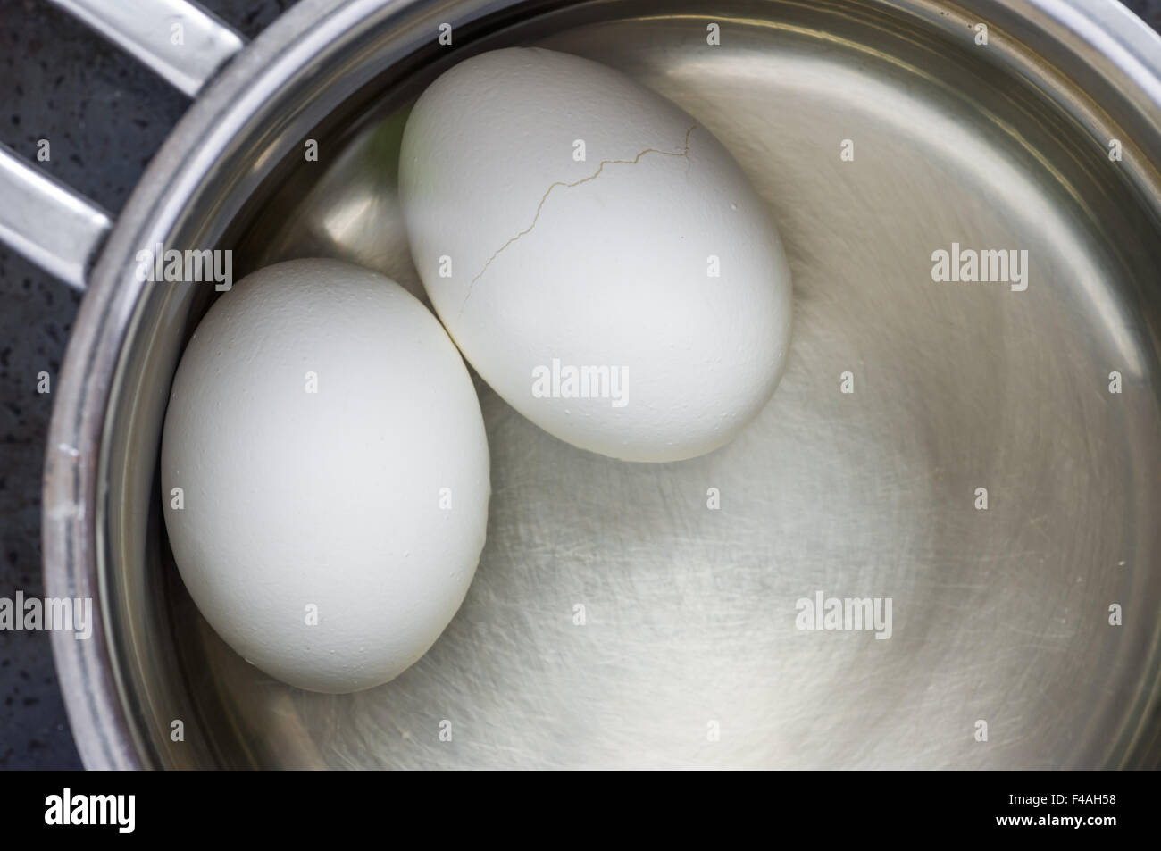 Eggs boil in boiling water in a steel pot top view Stock Photo - Alamy