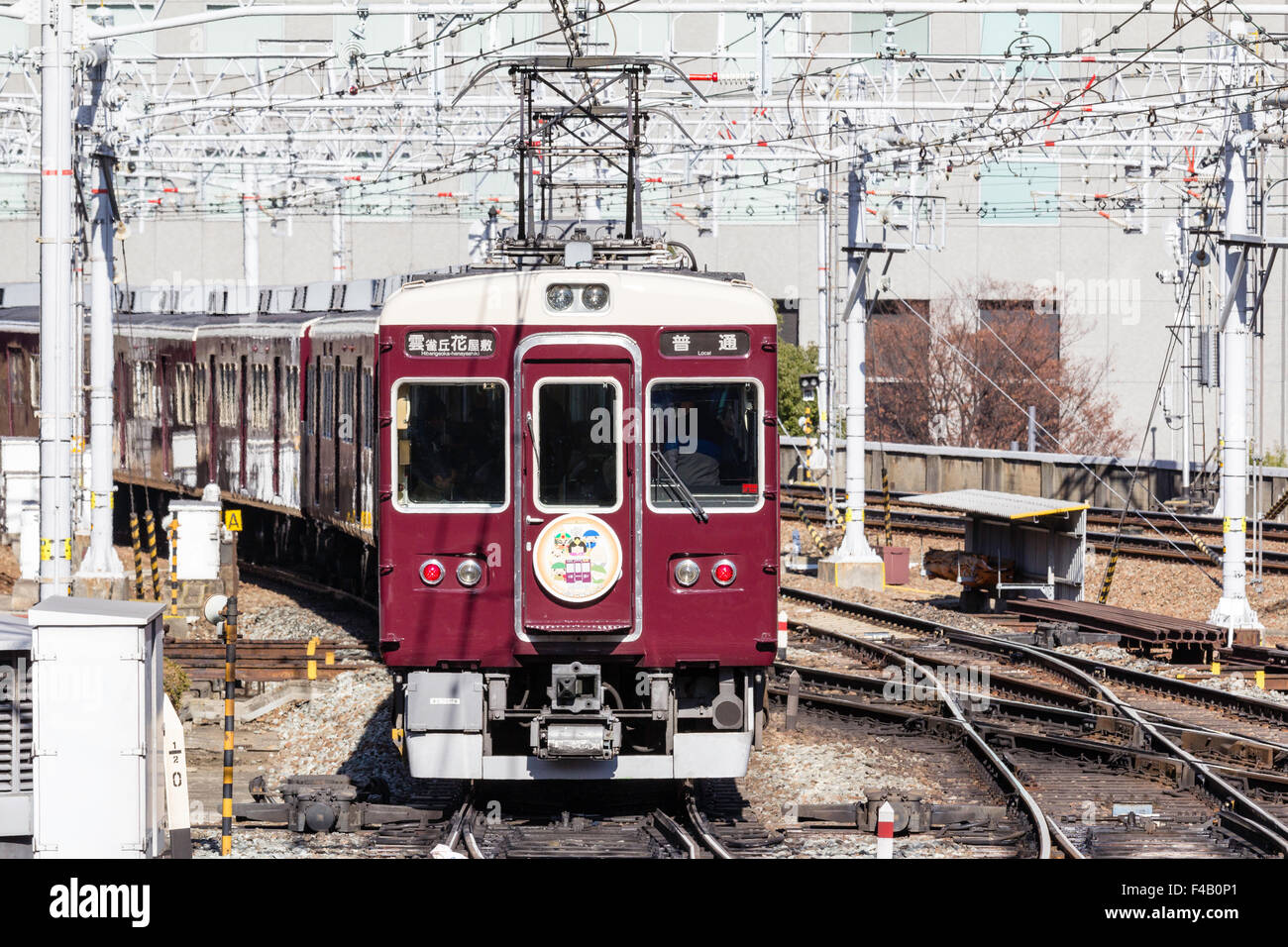 Japan, Osaka, Umeda. Private Hankyu railway, Maroon coloured train with ...