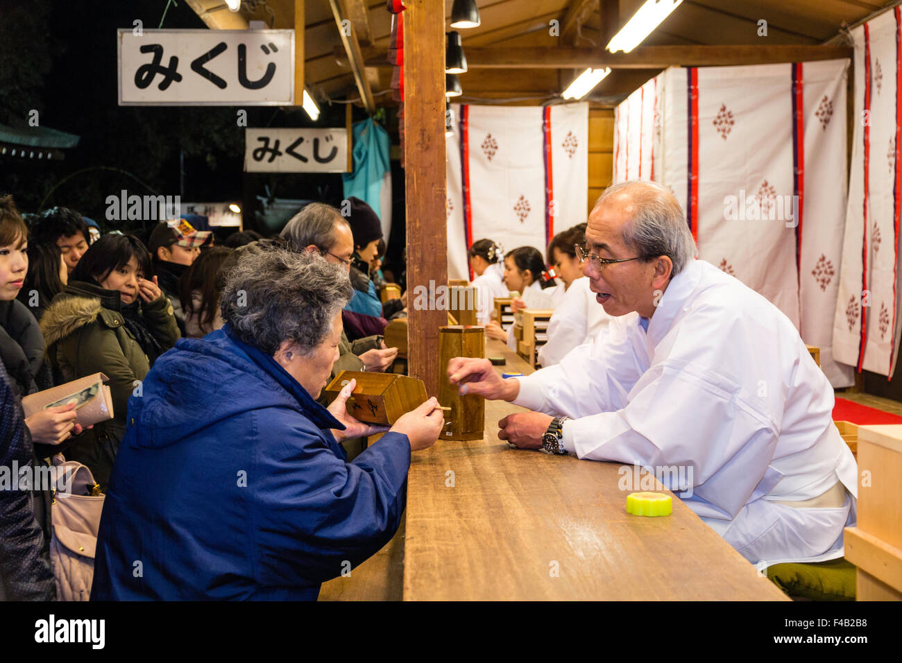 Japan, Nishinomiya shrine, New year Day, Shogatsu. Senior woman buying ...