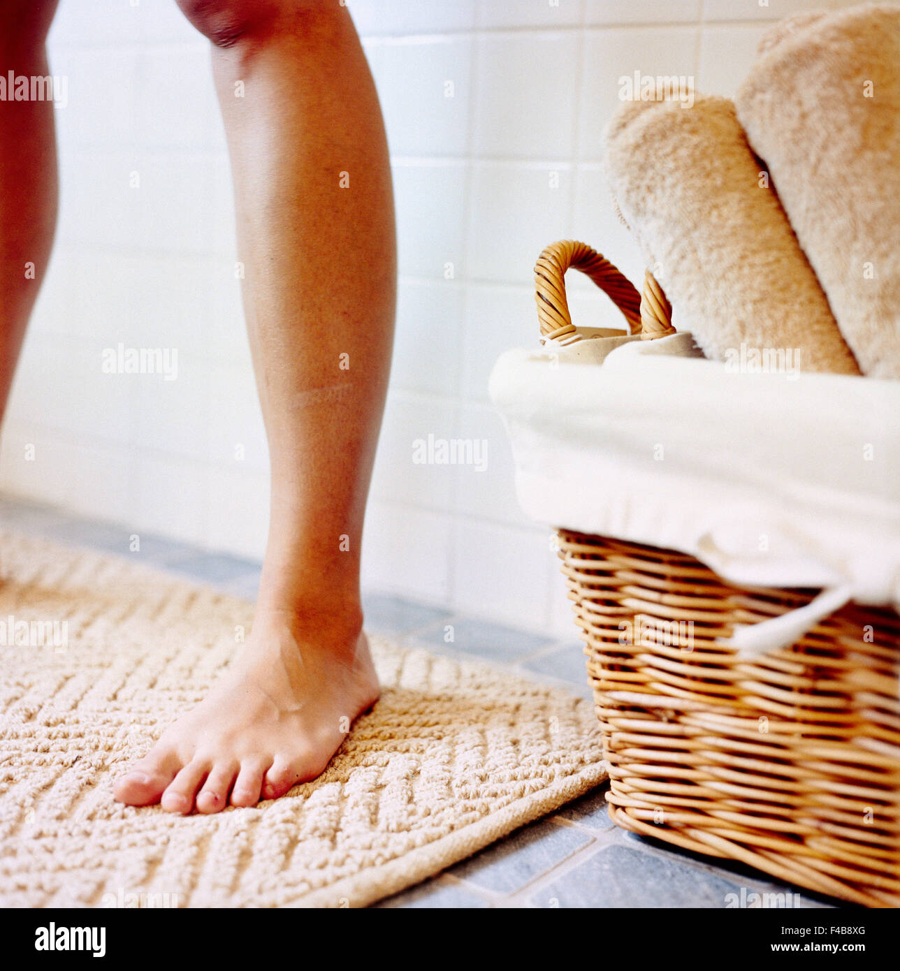 Barefoot on the bathroom rug beside basket with towels Stock Photo - Alamy