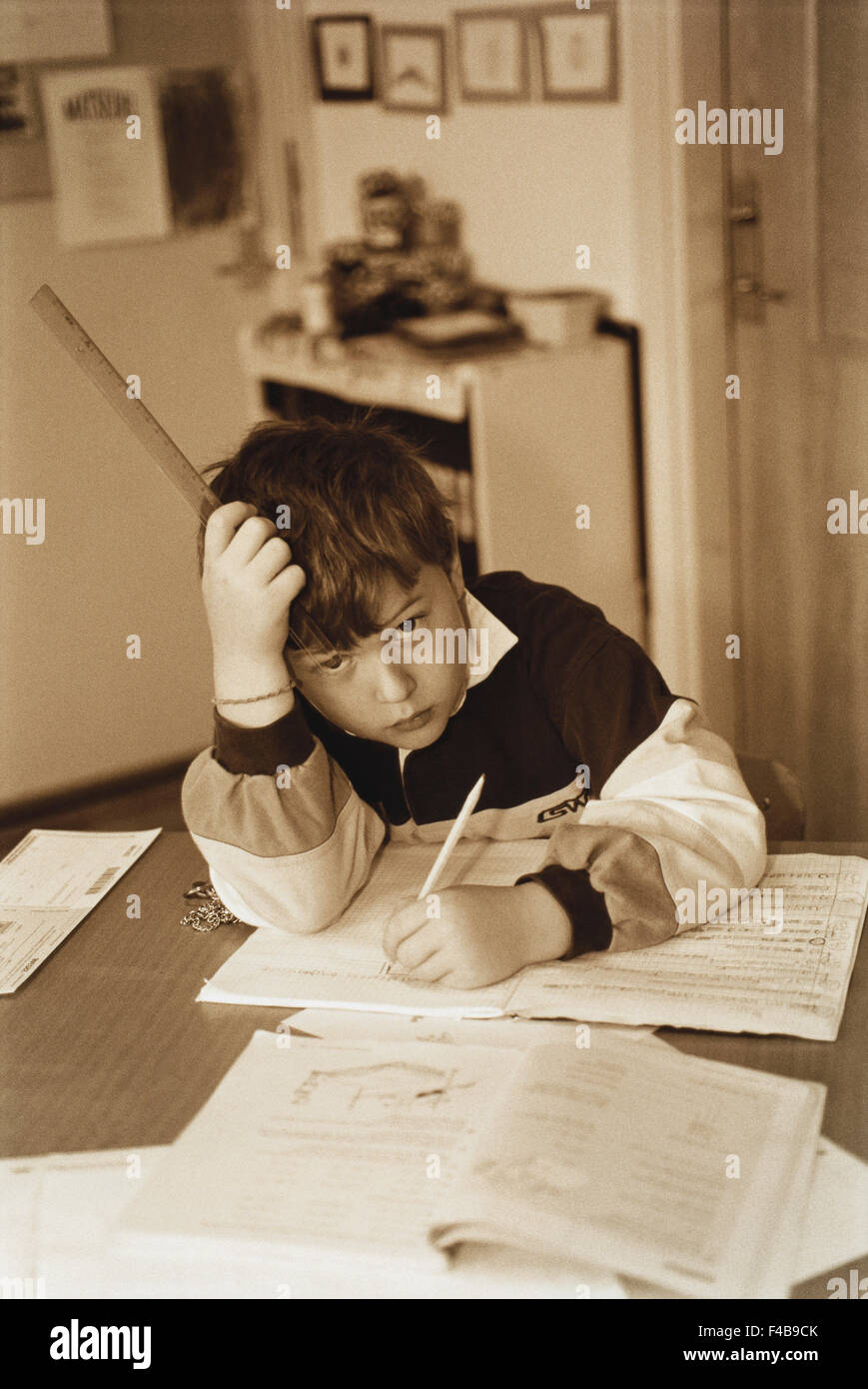 A boy sitting at a school bench and writing in a book Stock Photo - Alamy