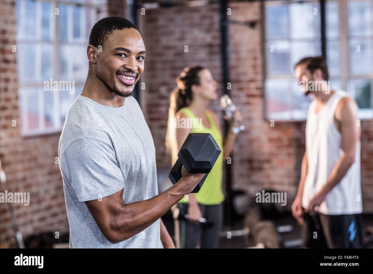 Smiling muscular man lifting a dumbbell Stock Photo - Alamy