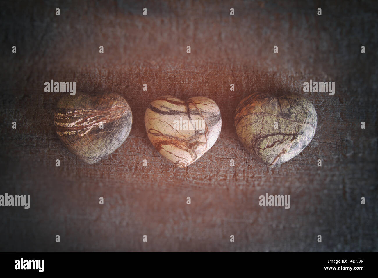 Three stone hearts on wood background Stock Photo - Alamy