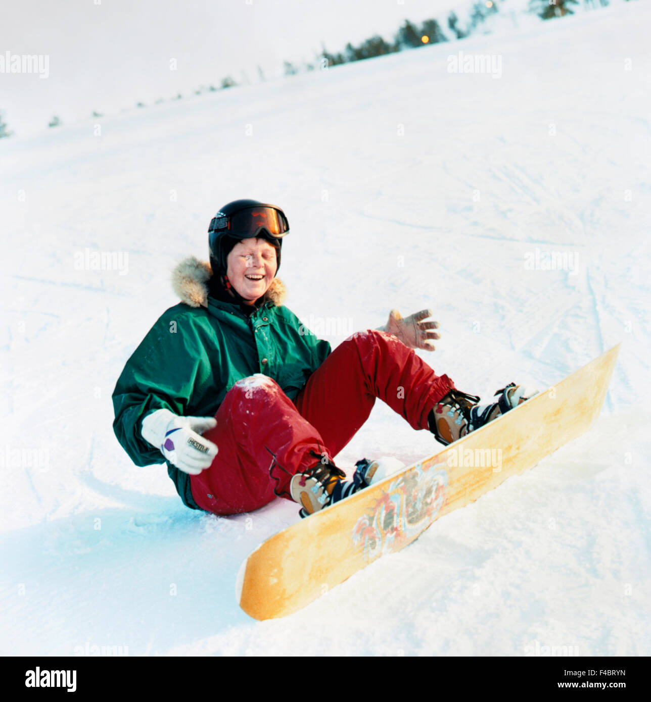 Woman with snowboard sitting on the ground, laughing Stock Photo - Alamy