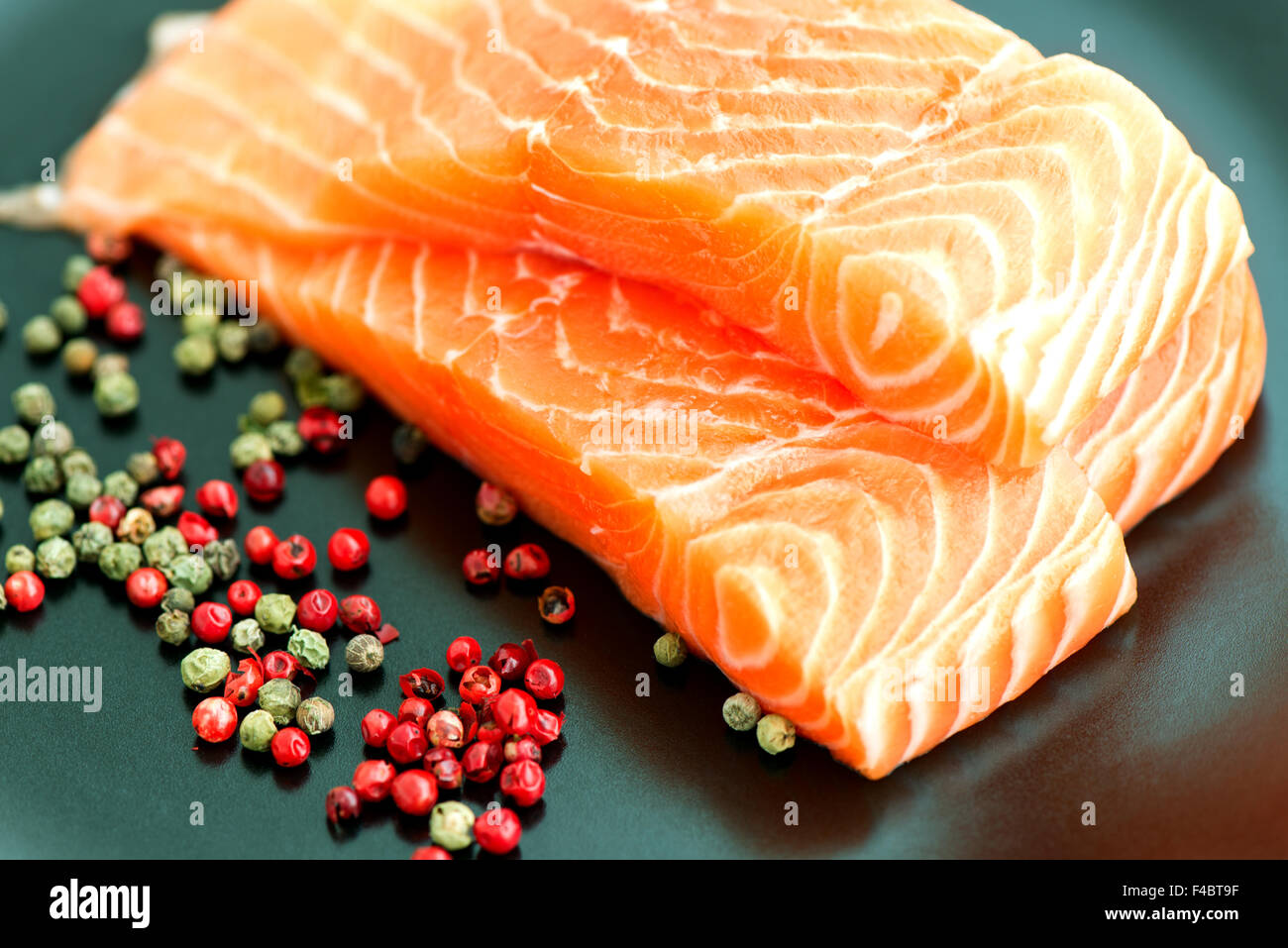 Raw salmon ready to cook close up on black surface Stock Photo - Alamy