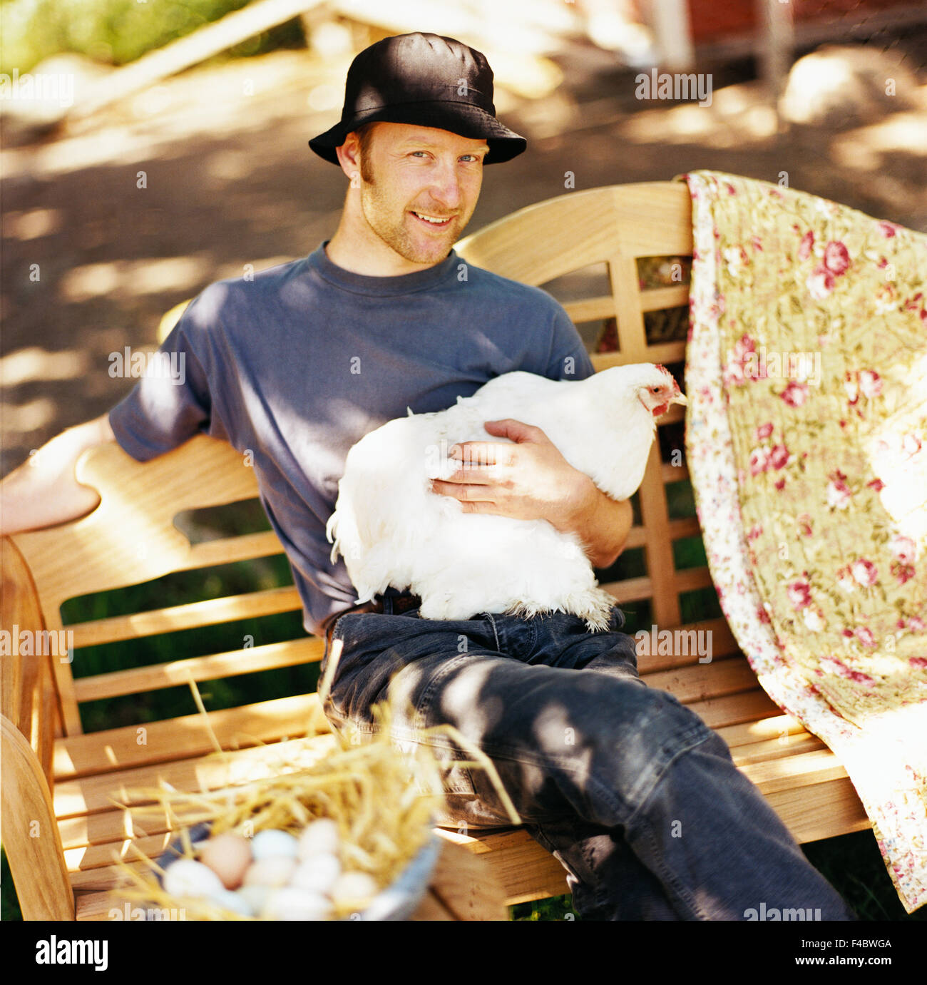 Smiling man holding a chicken in his arms Stock Photo - Alamy