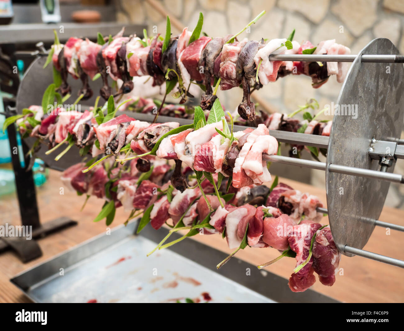 birds on the spit with meat, bacon and sage ready for roasting Stock ...