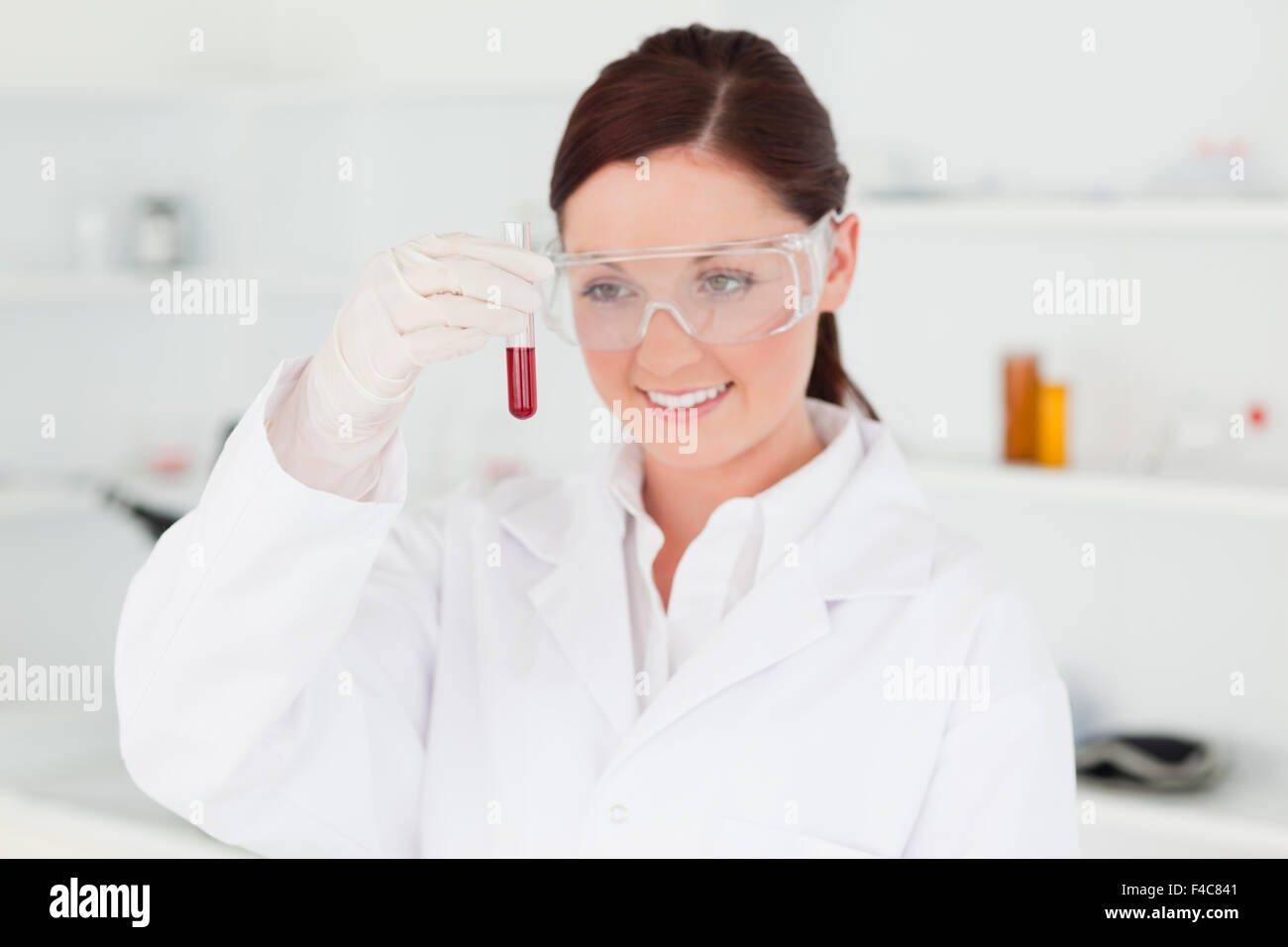 Cute red-haired scientist looking at a test tube in a lab Stock Photo ...