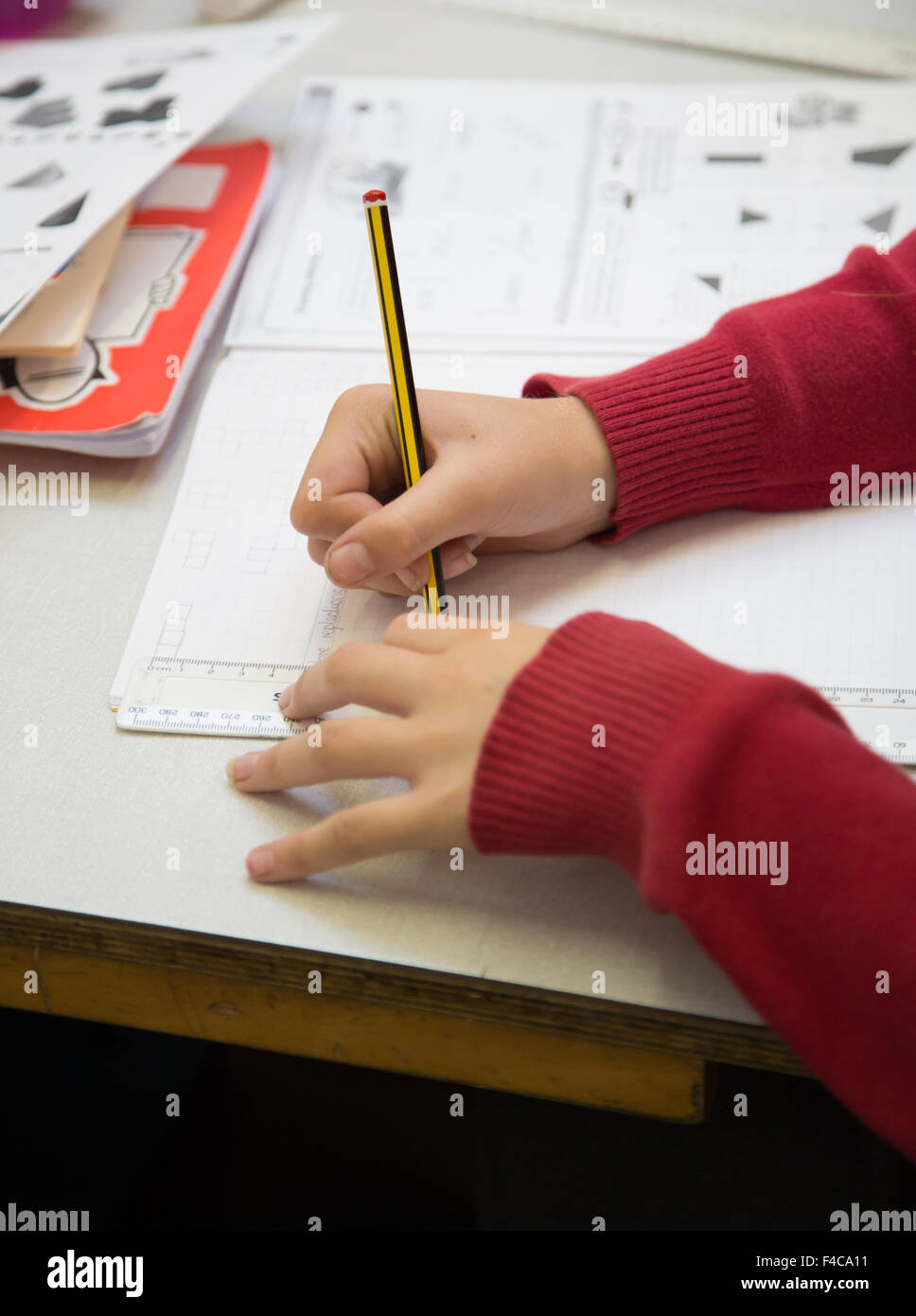 A typical UK primary school classroom with a pupil drawing a line with ...