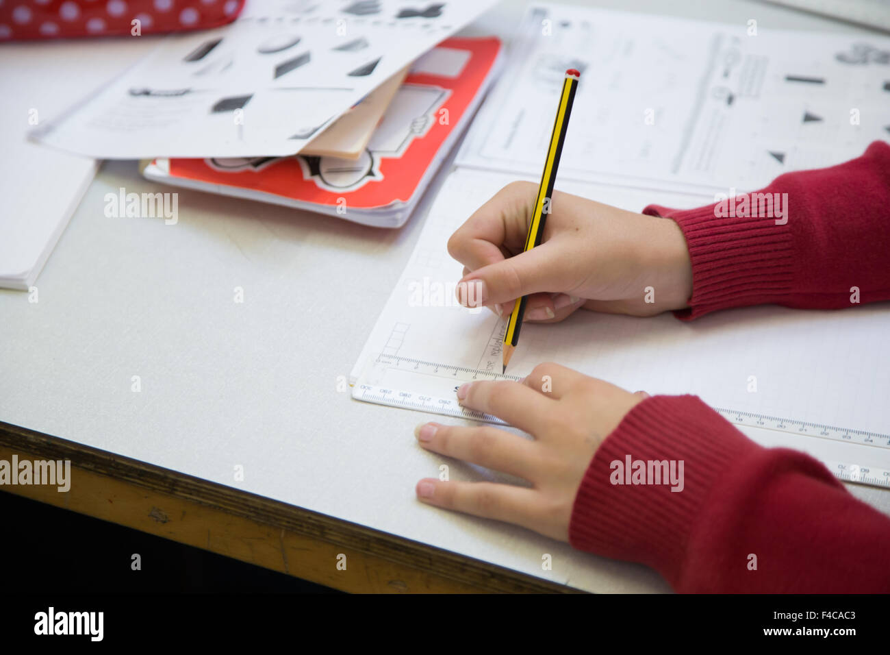 A typical UK primary school classroom with a pupil drawing a line with ...