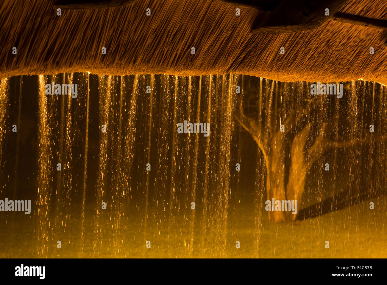 Africa, Namibia. Rain pouring off thatched roof. Credit as: Bill Young ...