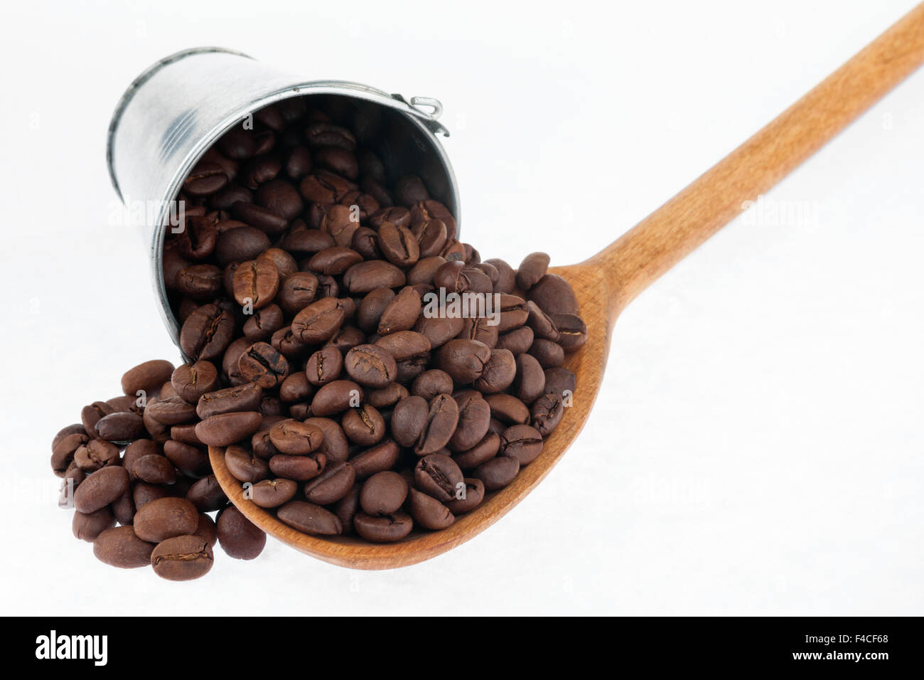 Bucket of coffee beens crumbles in the a wooden spoon, on a white ...