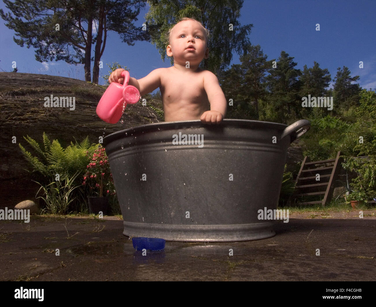 A Baby Bathing in a Barrel with a Watering Can Stock Photo - Alamy