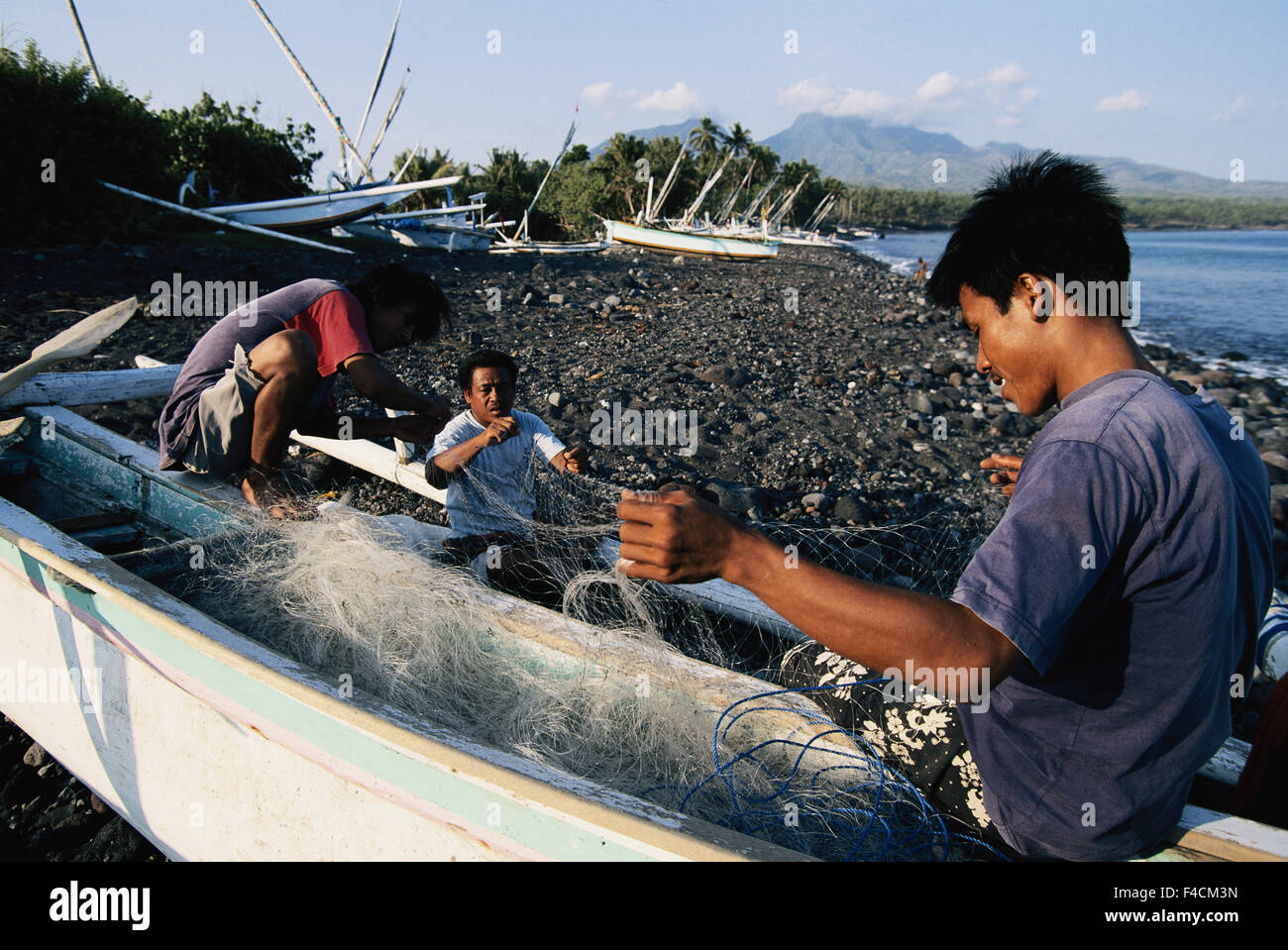 Indonesia, Bali, Fisherman repairing nets by outrigger. (Large format ...
