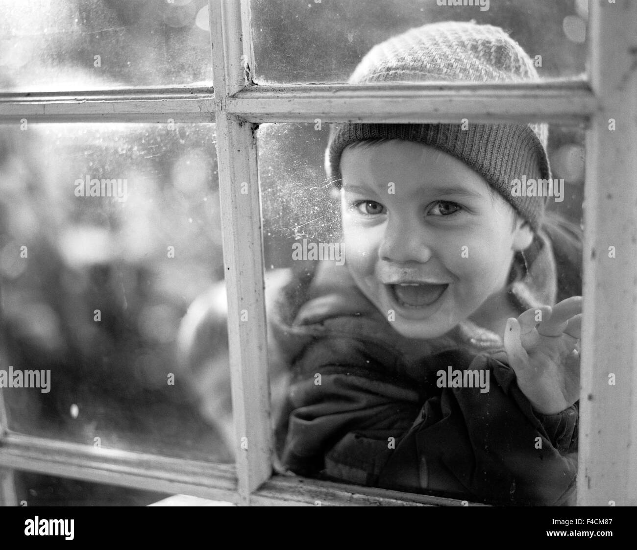 Small boy laughing and looking through window Stock Photo - Alamy
