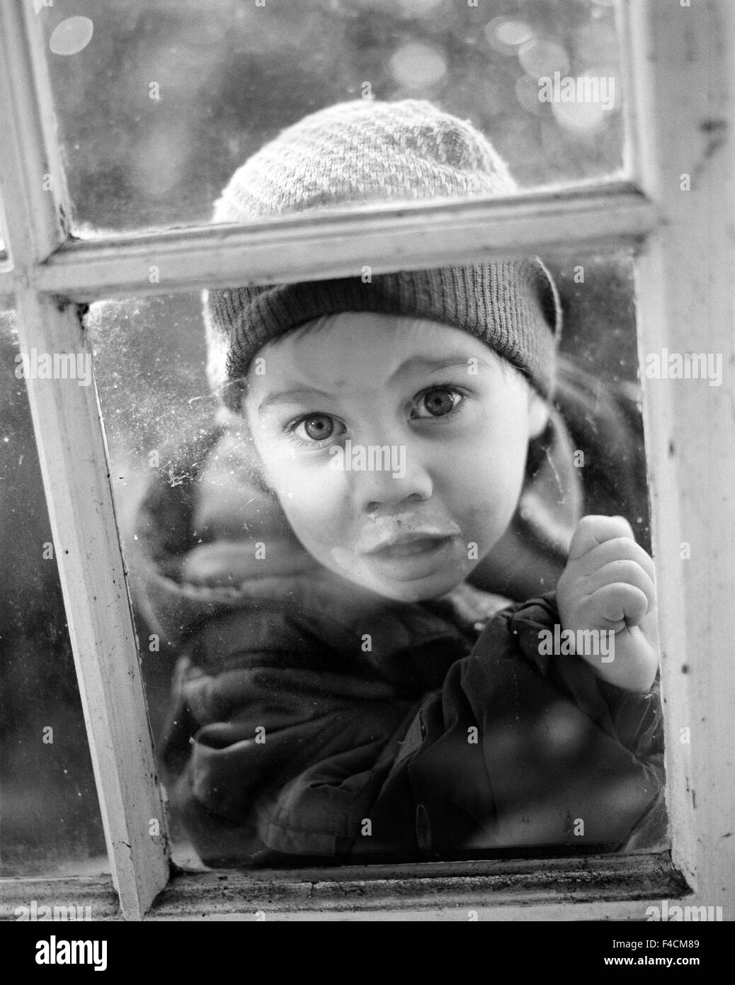Small boy looking through window Stock Photo - Alamy
