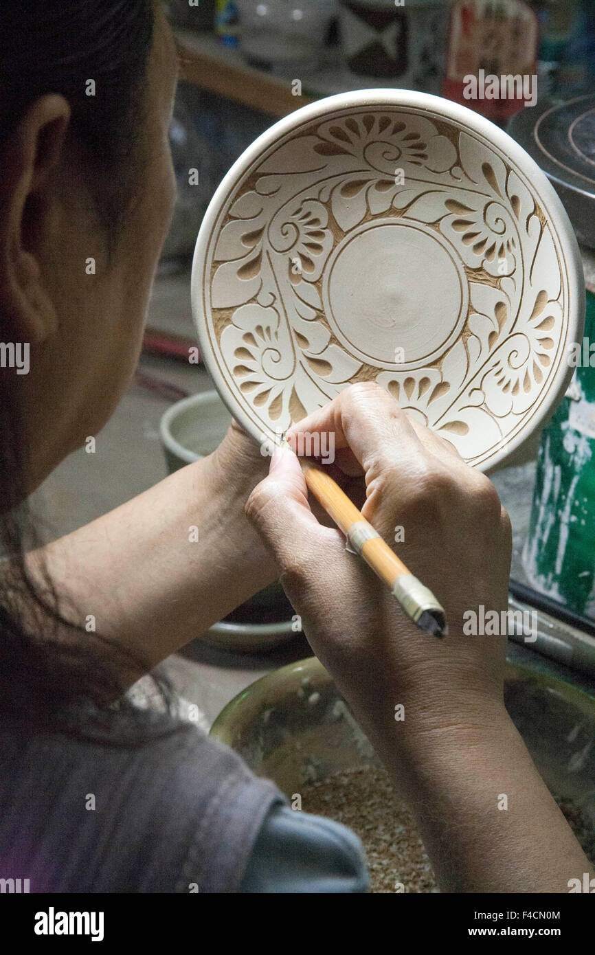 Ceramics craftsman at work on Tsuboya ware bowl at kiln in Naha ...
