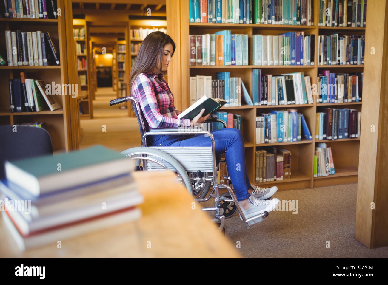 Disabled female student reading book in library Stock Photo - Alamy