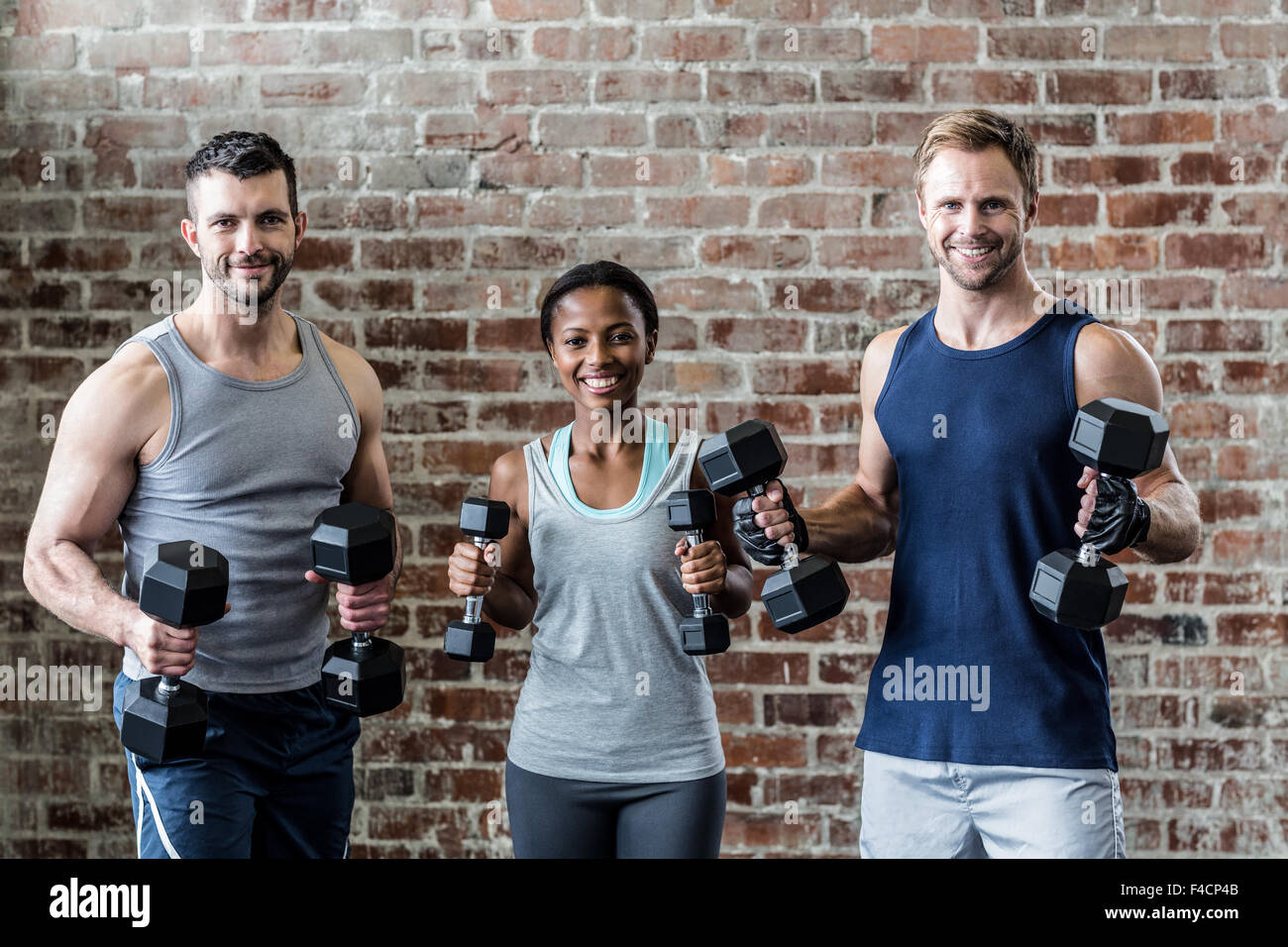 Fit smiling people lifting dumbbells together Stock Photo - Alamy