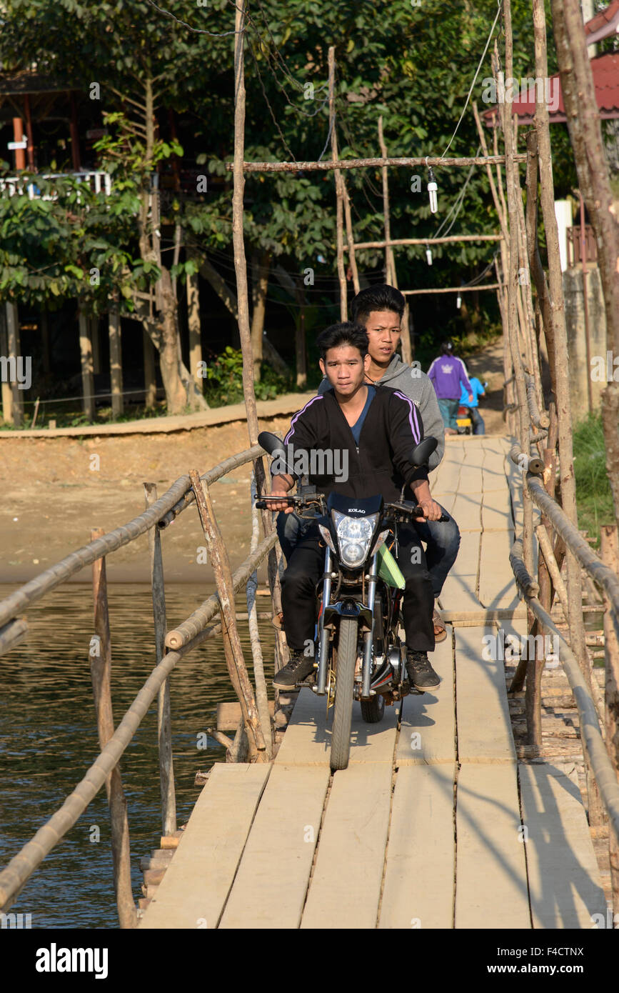 Laos, Vang Vieng. Men on motor scooter crossing foot bridge Stock Photo ...