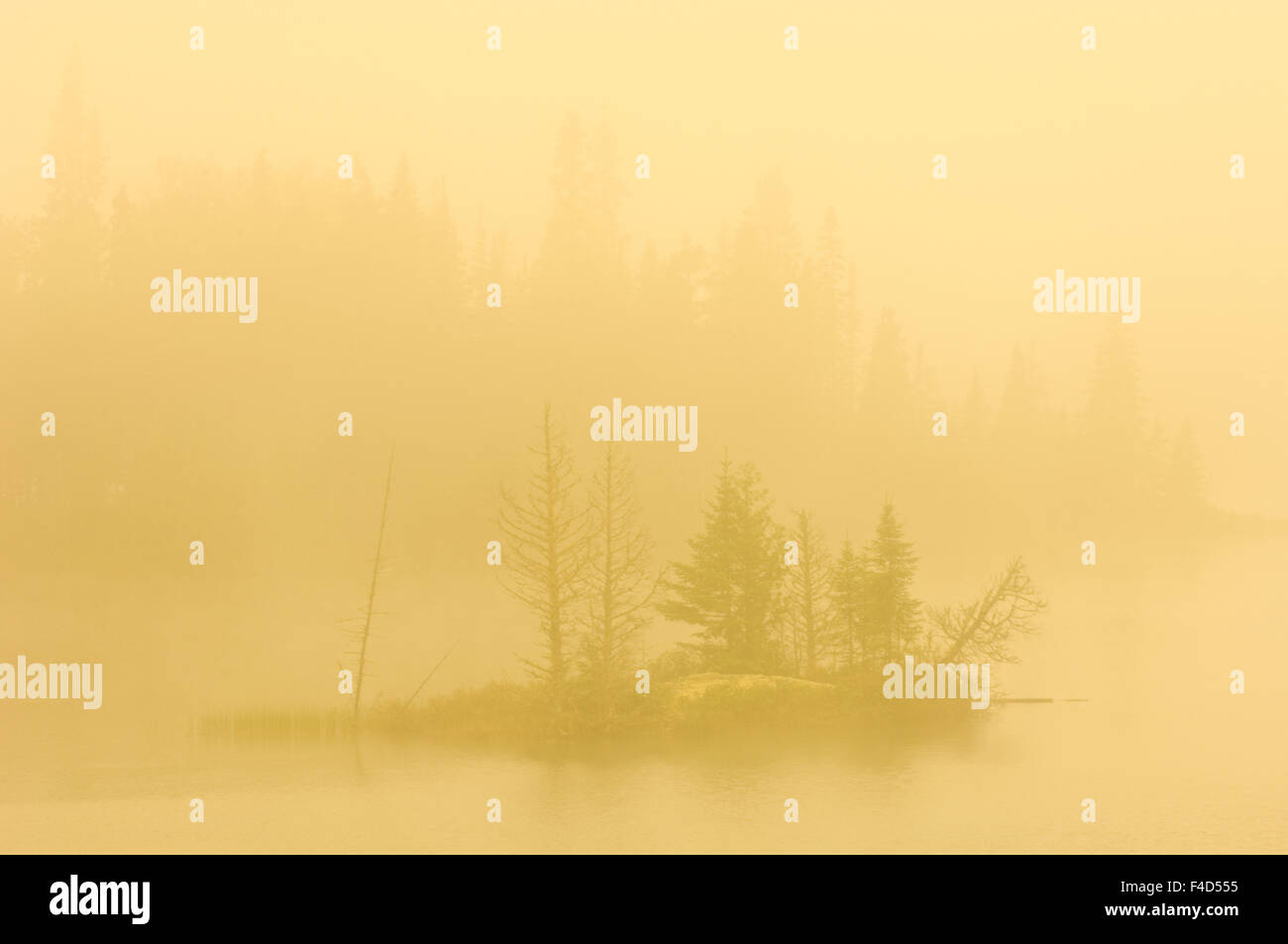 Canada, Ontario. Heavy morning fog on lake with small island. Credit as ...