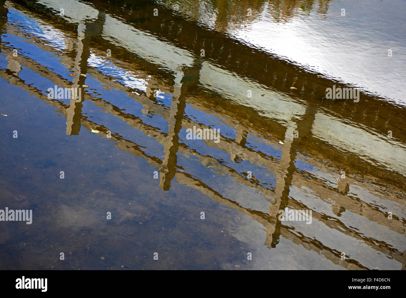 A reflection of a footbridge in a small river in the Norfolk ...
