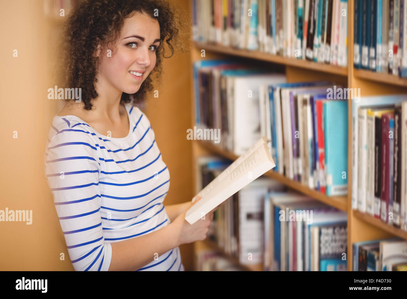 Pretty student in library reading book Stock Photo - Alamy