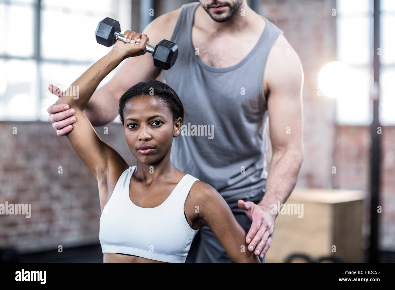 Personal trainer working with client holding dumbbell Stock Photo - Alamy