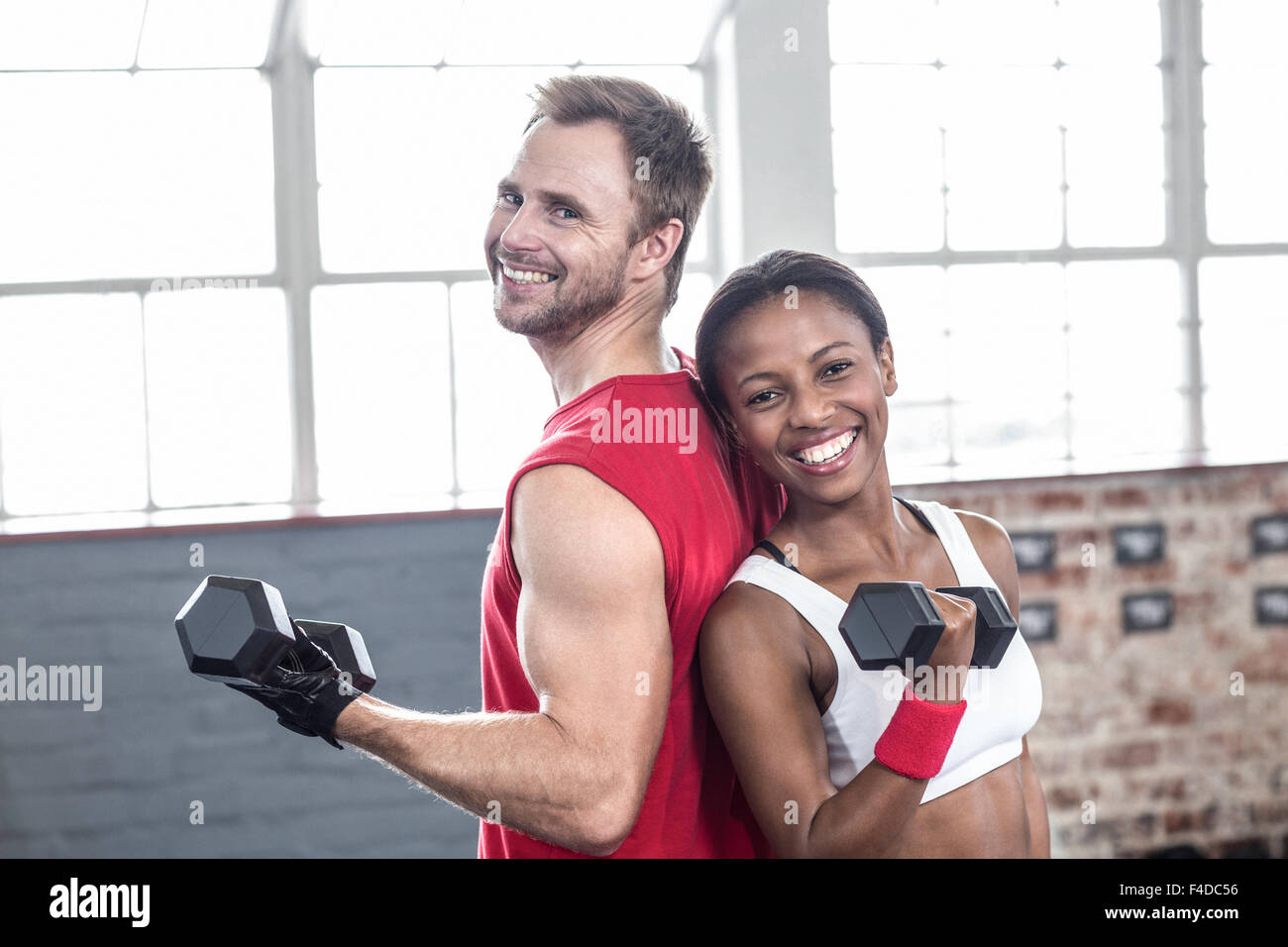 Smiling muscular couple lifting weight Stock Photo - Alamy