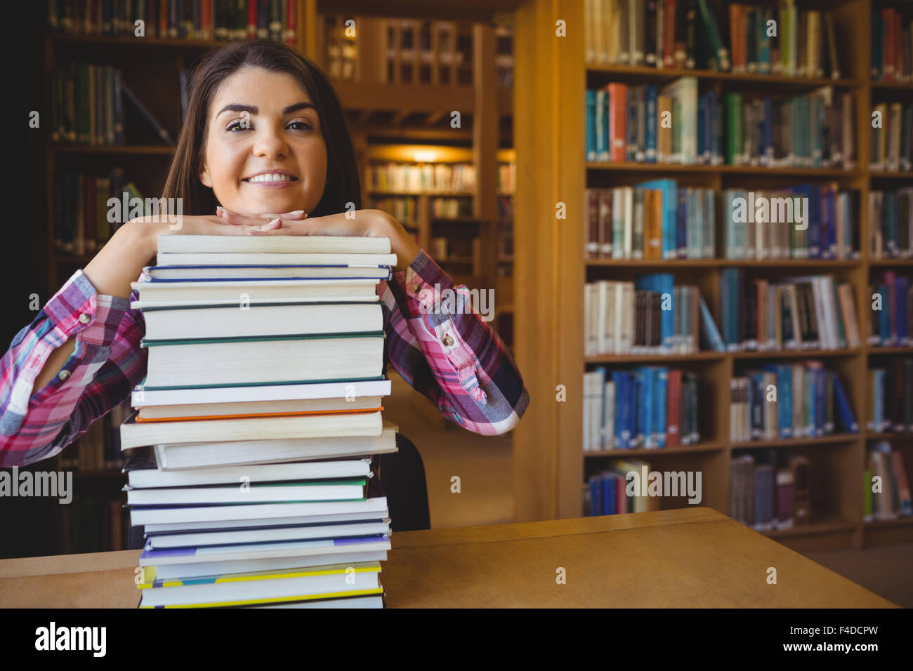 Happy female student leaning on book stack Stock Photo - Alamy
