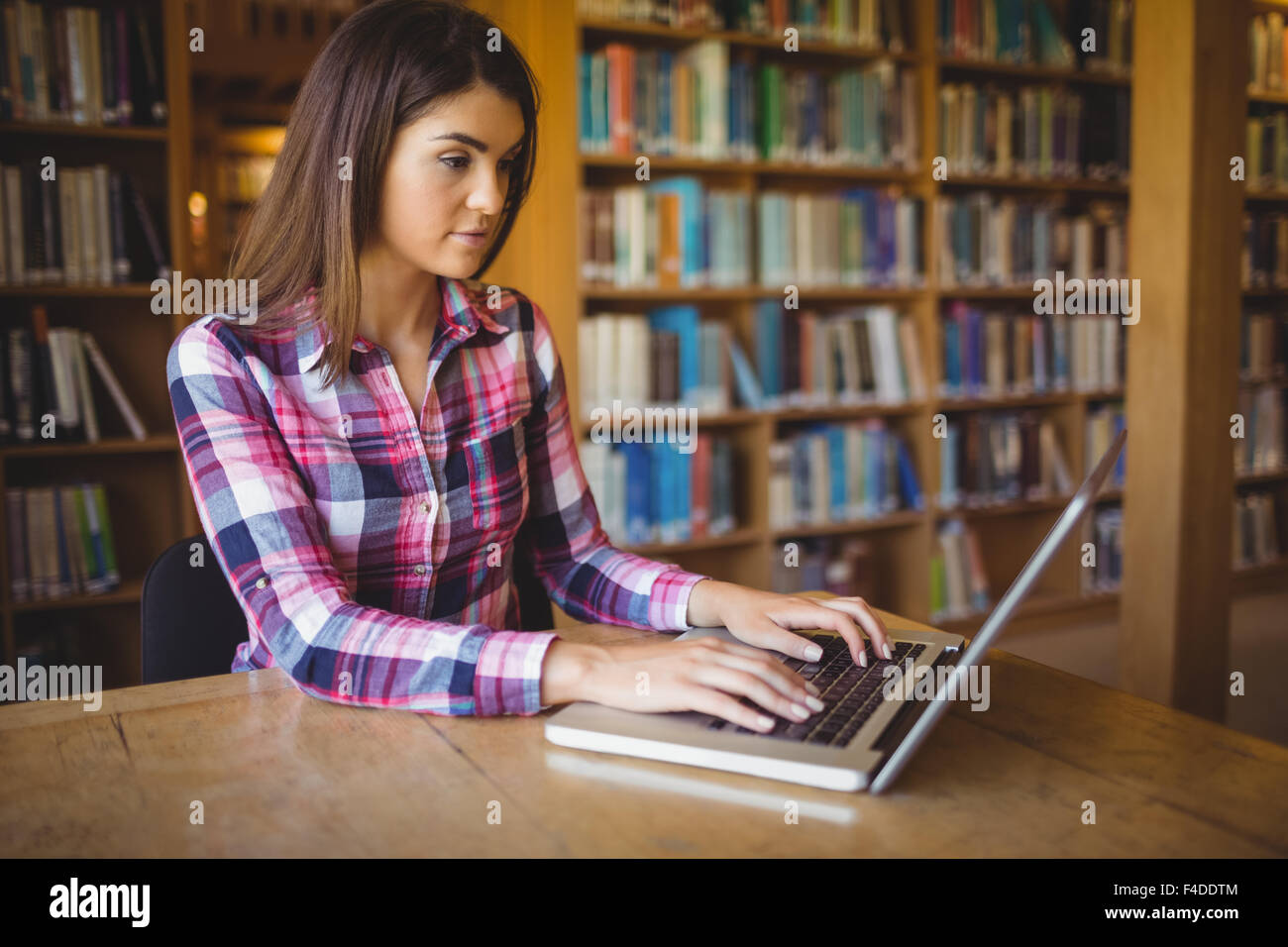 Thoughtful female student typing on laptop Stock Photo - Alamy