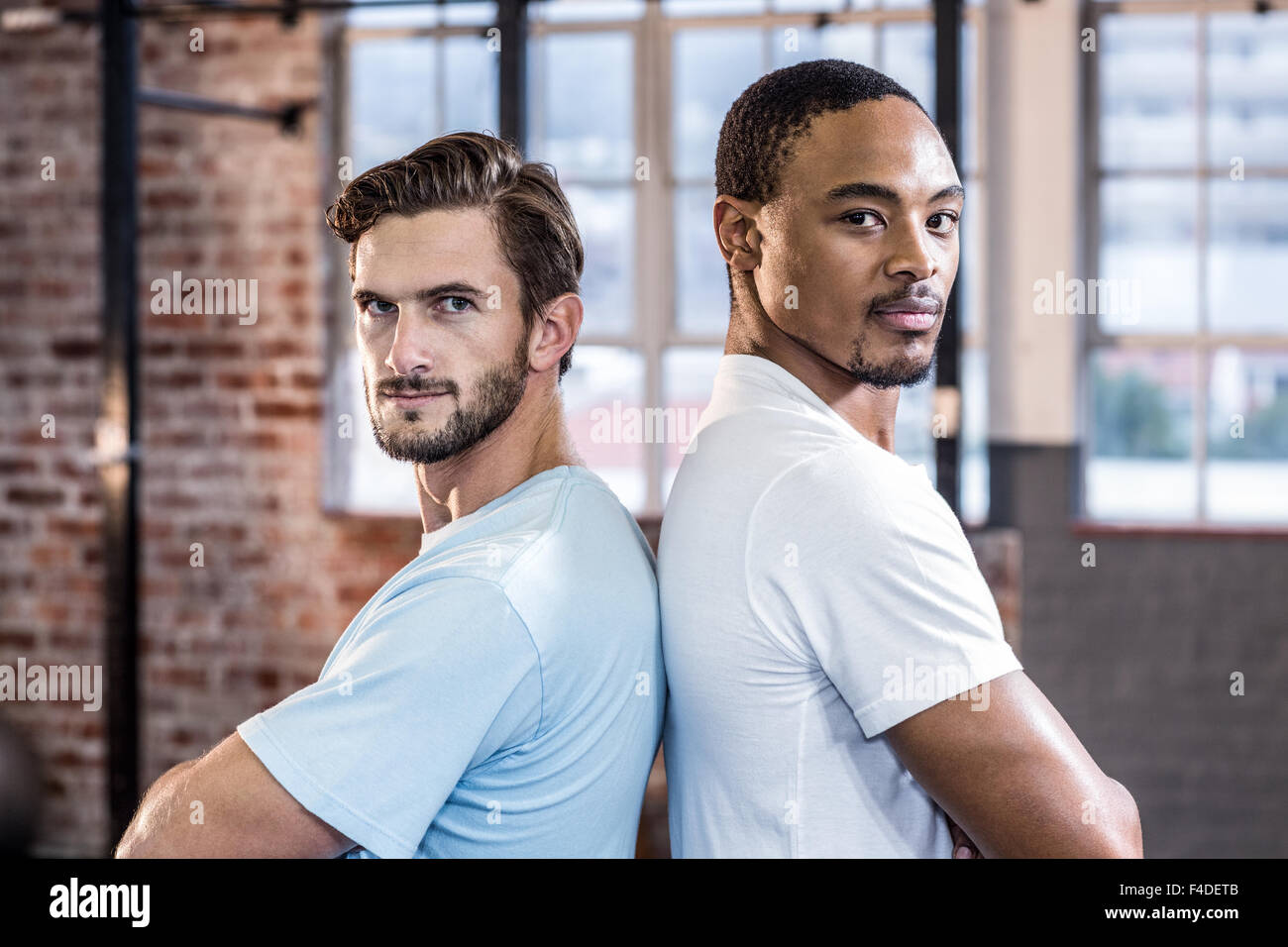 Muscular athletes standing back to back in gym Stock Photo - Alamy