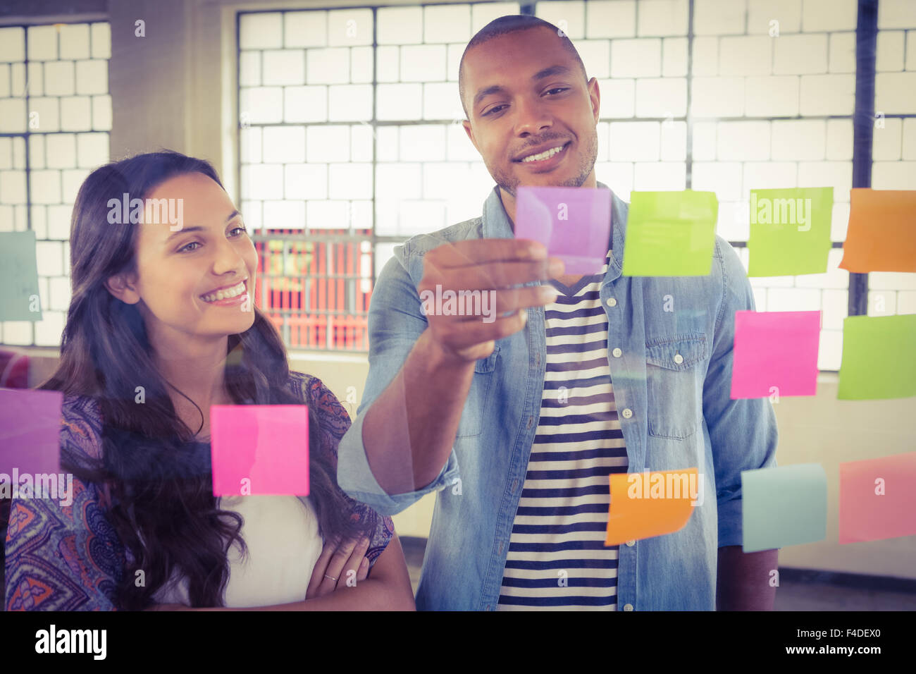 Creative team looking at sticky notes on glass window Stock Photo - Alamy