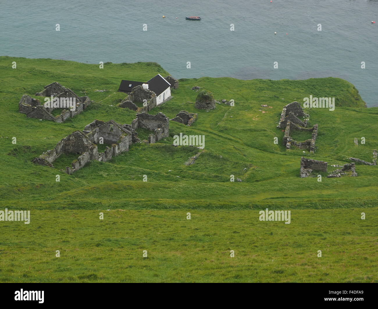 High view of white house and ruins of abandoned stone dwellings on ...
