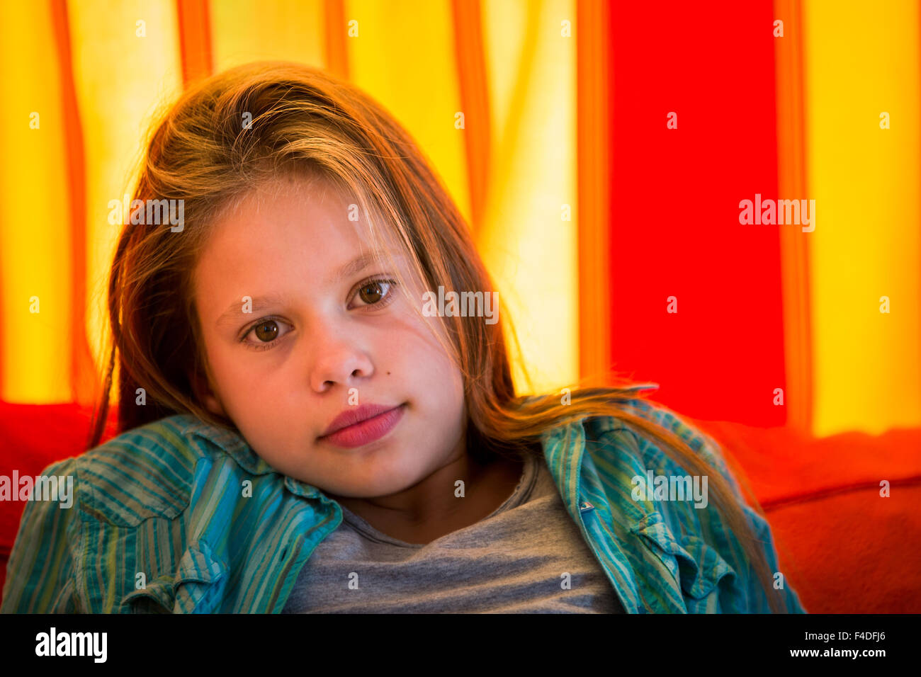 Head Shot Of A Beautiful 11 Years Old Girl Sitting In Front Of A Red