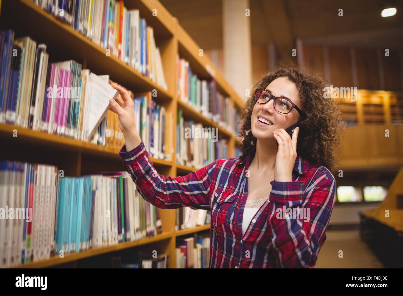 Pretty student in the library taking book Stock Photo - Alamy