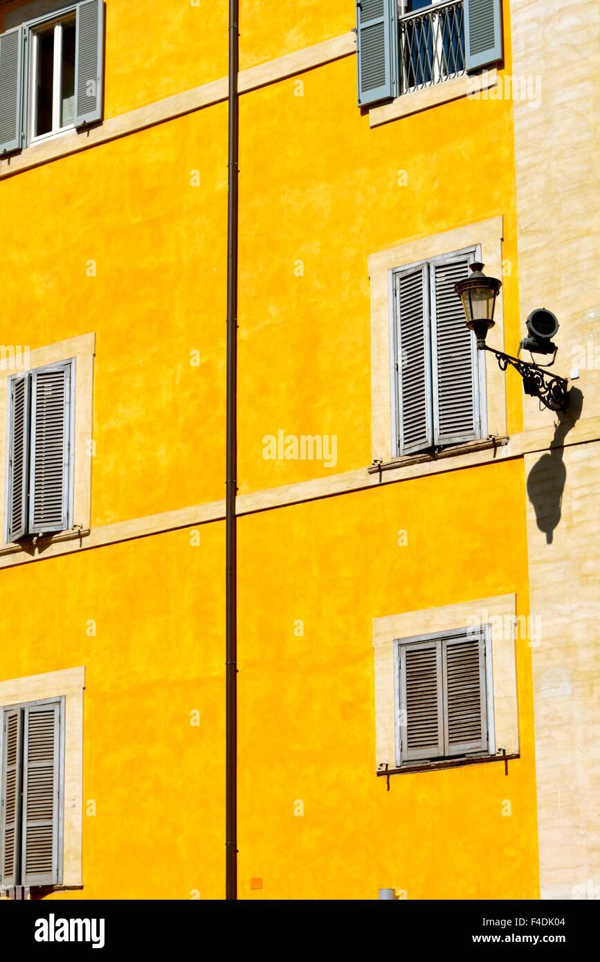 windows on a yellow painted wall of an apartment building in Rome Italy ...