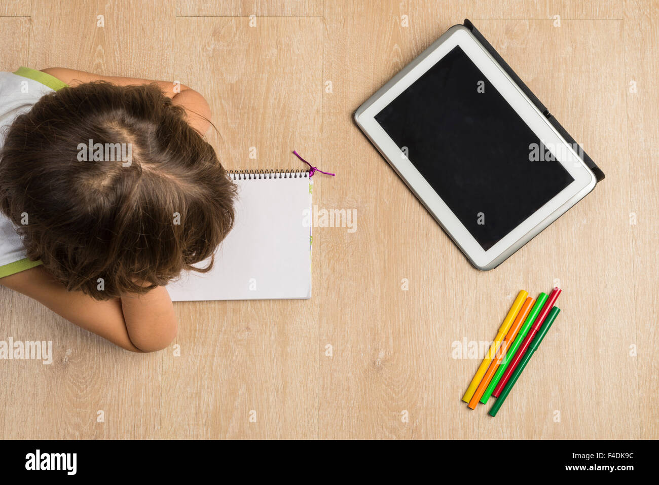 Little girl doing homework lying on the floor with a notebook and a ...