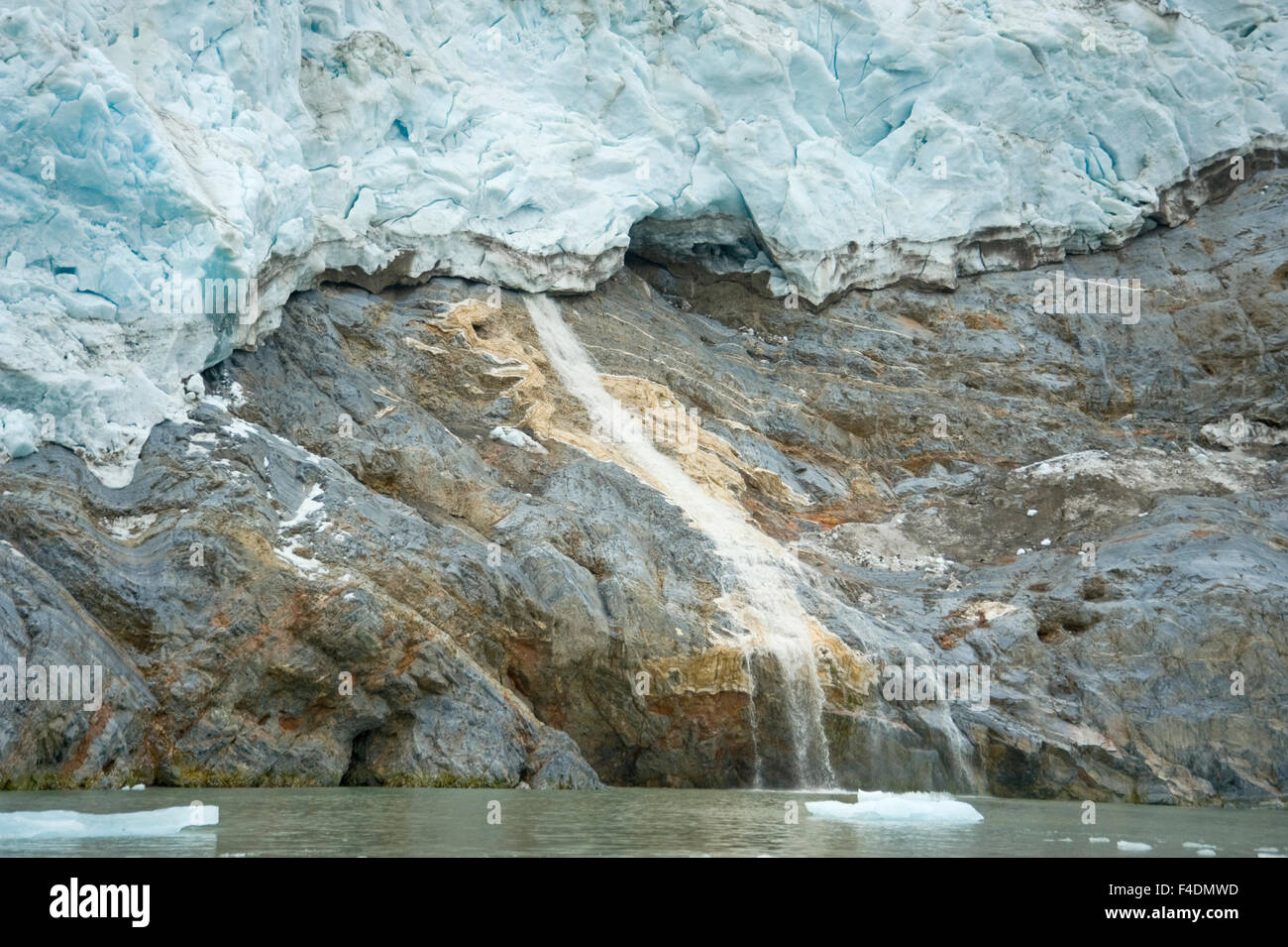 Norway, Spitsbergen. Melting glacial ice creates a runoff waterfall and ...
