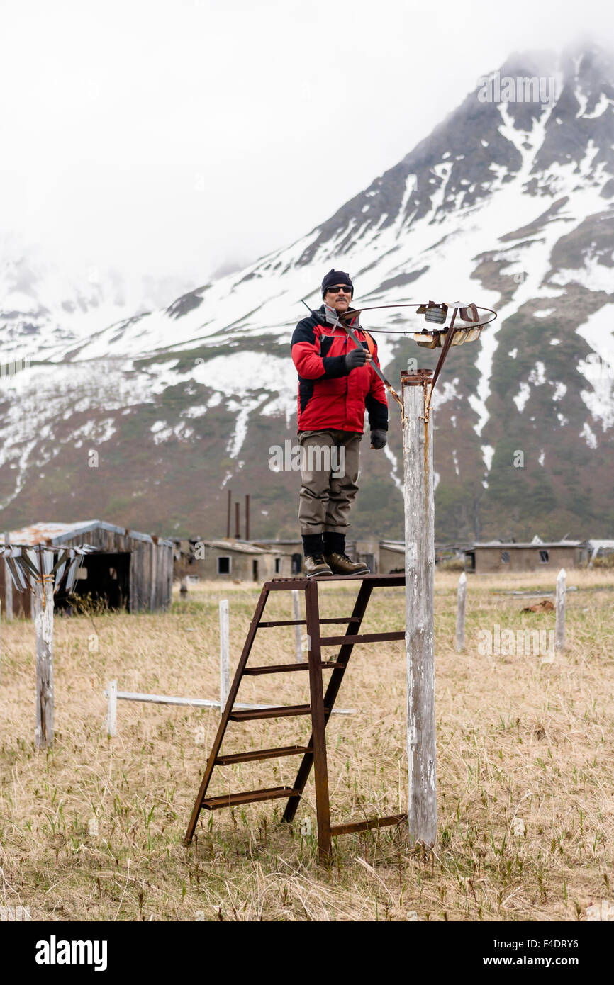 Russia, Kamchatka, Lavrova Bay, Man on ladder next to pole (MR Stock ...