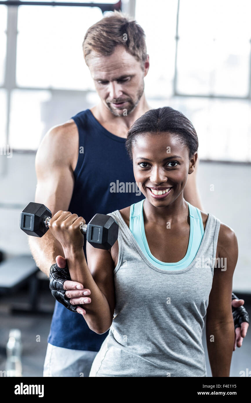 Male trainer assisting woman with dumbbell Stock Photo - Alamy