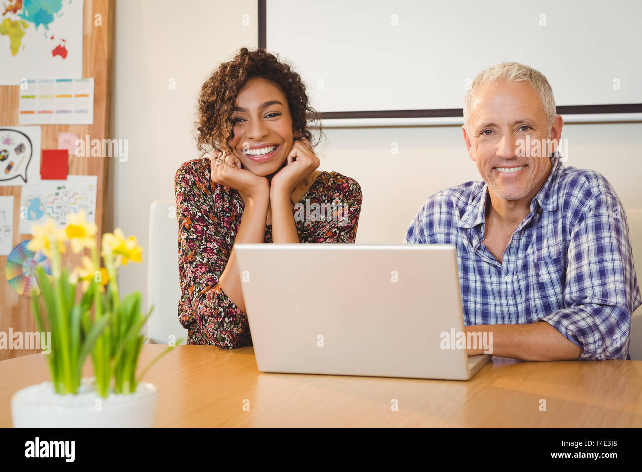 Portrait of happy business people sitting at desk by laptop Stock Photo ...