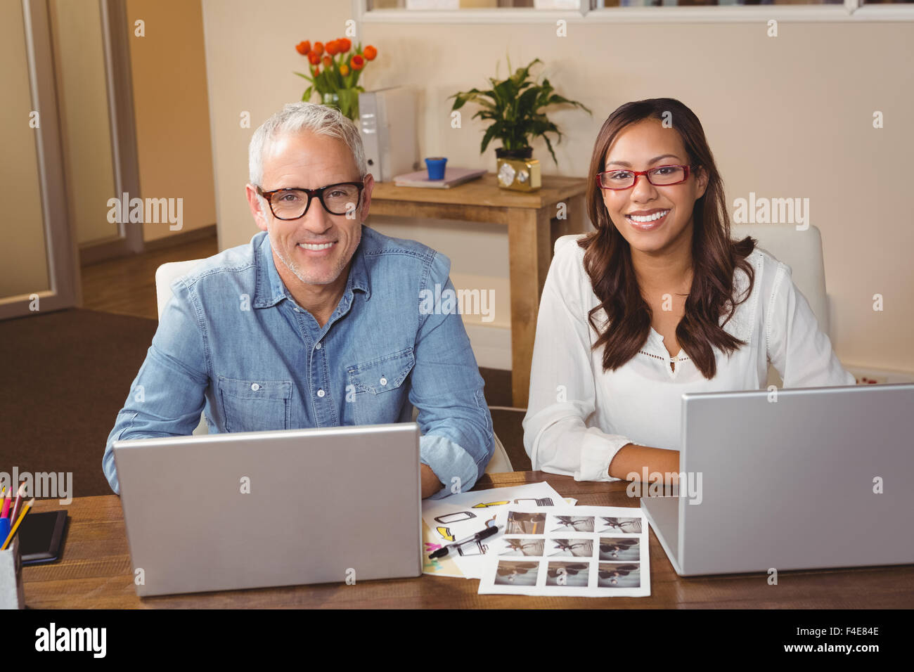 Creative business people with laptop at desk in office Stock Photo - Alamy