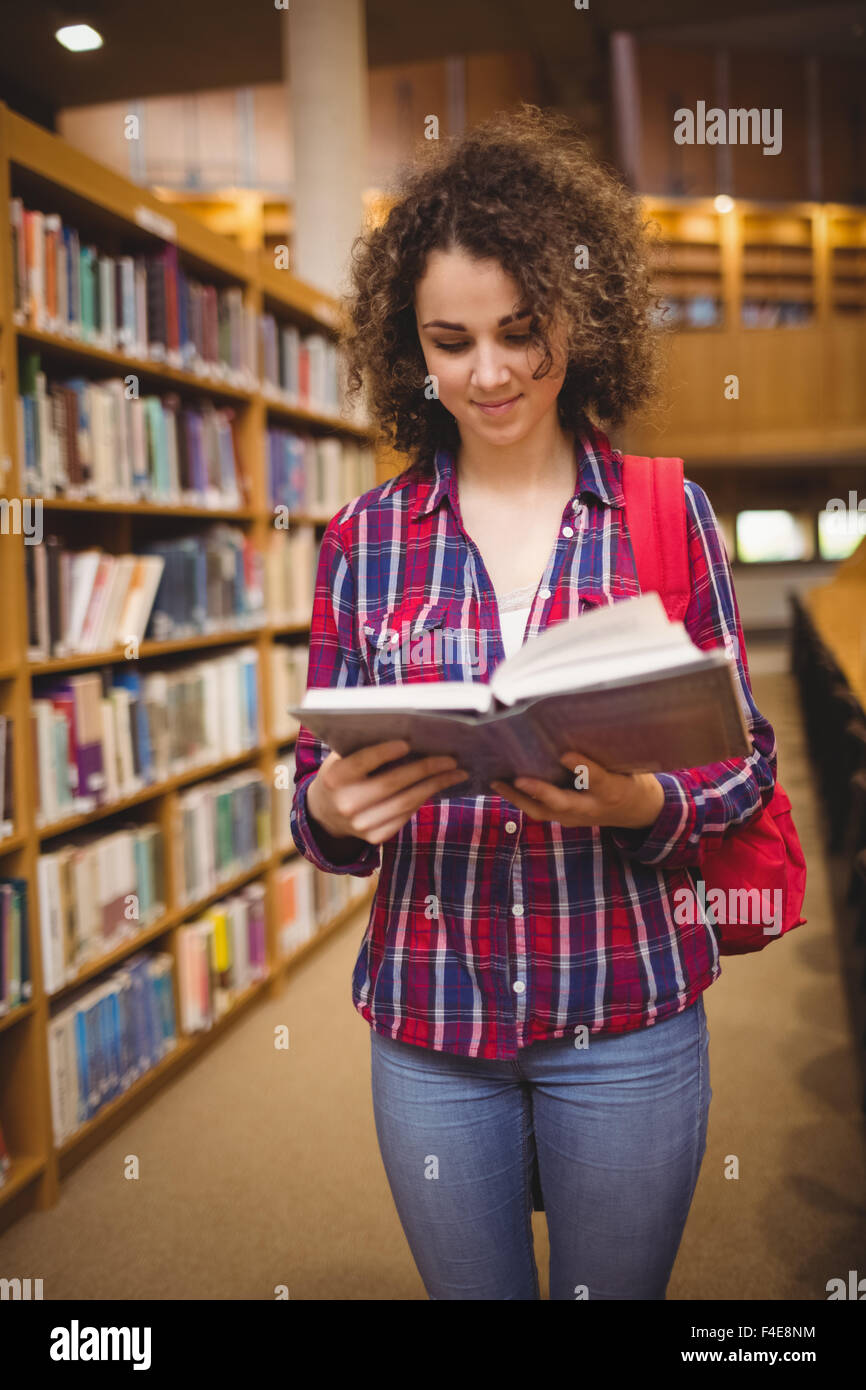 Pretty student in the library reading book Stock Photo - Alamy