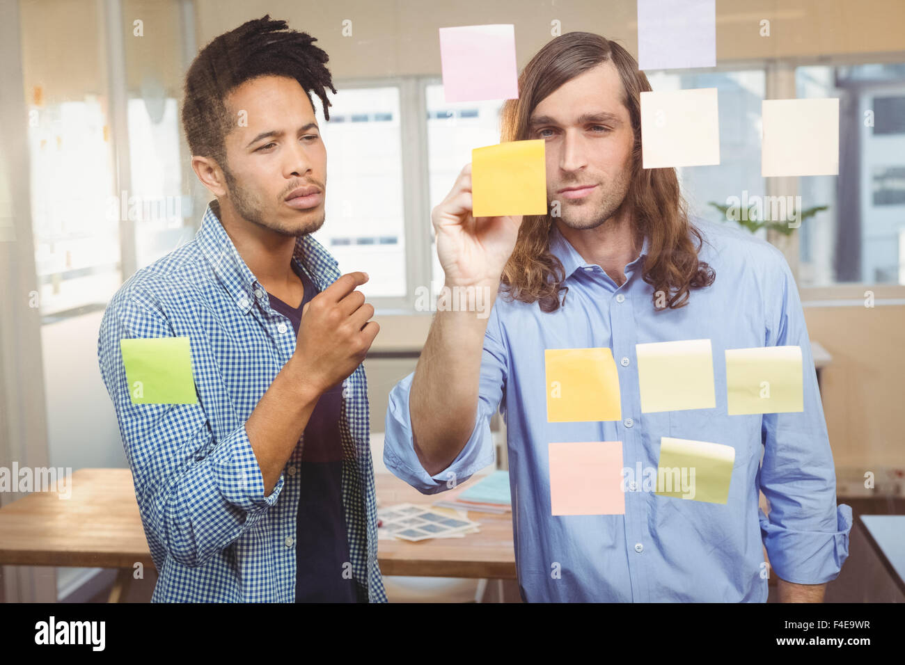 Businessman writing while colleague watching at sticky notes Stock ...