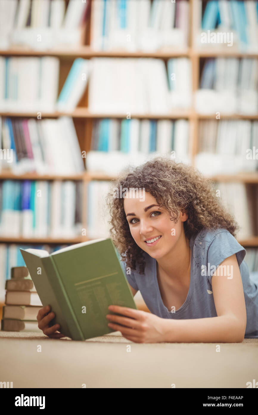 Pretty student in library reading book Stock Photo - Alamy