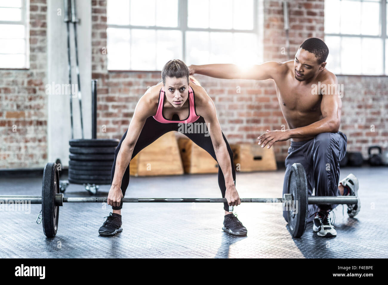 Trainer helping woman with lifting barbell Stock Photo - Alamy